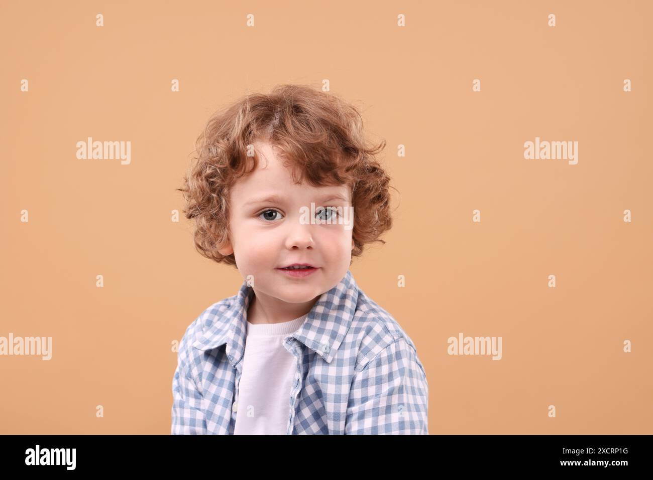 Portrait of cute little boy on beige background Stock Photo - Alamy