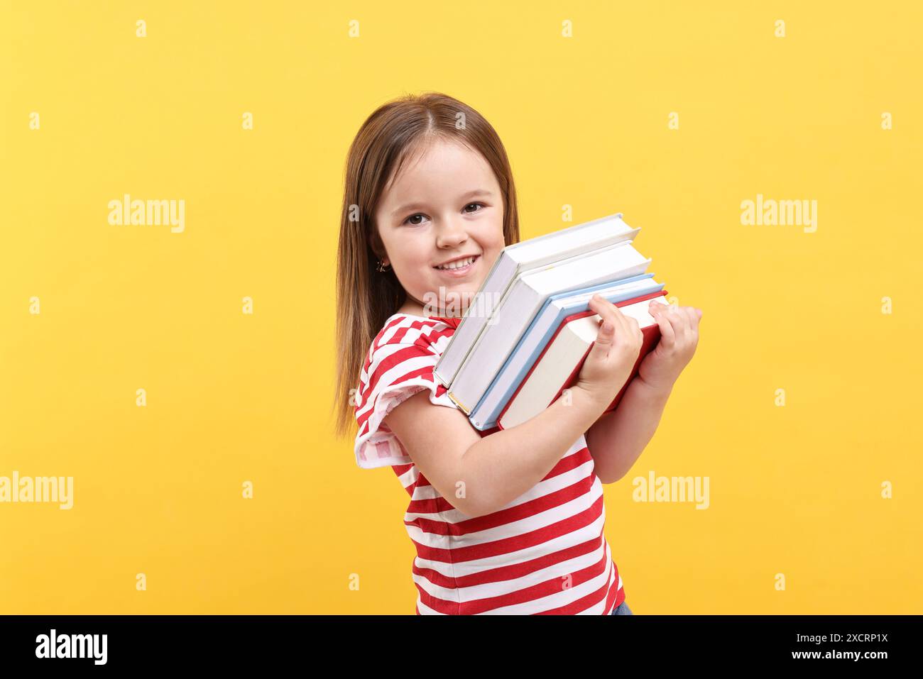 Little schoolgirl holding books hi-res stock photography and images - Alamy