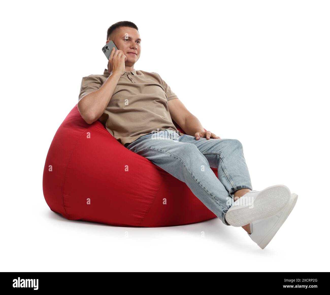 Handsome man talking by smartphone on red bean bag chair against white ...
