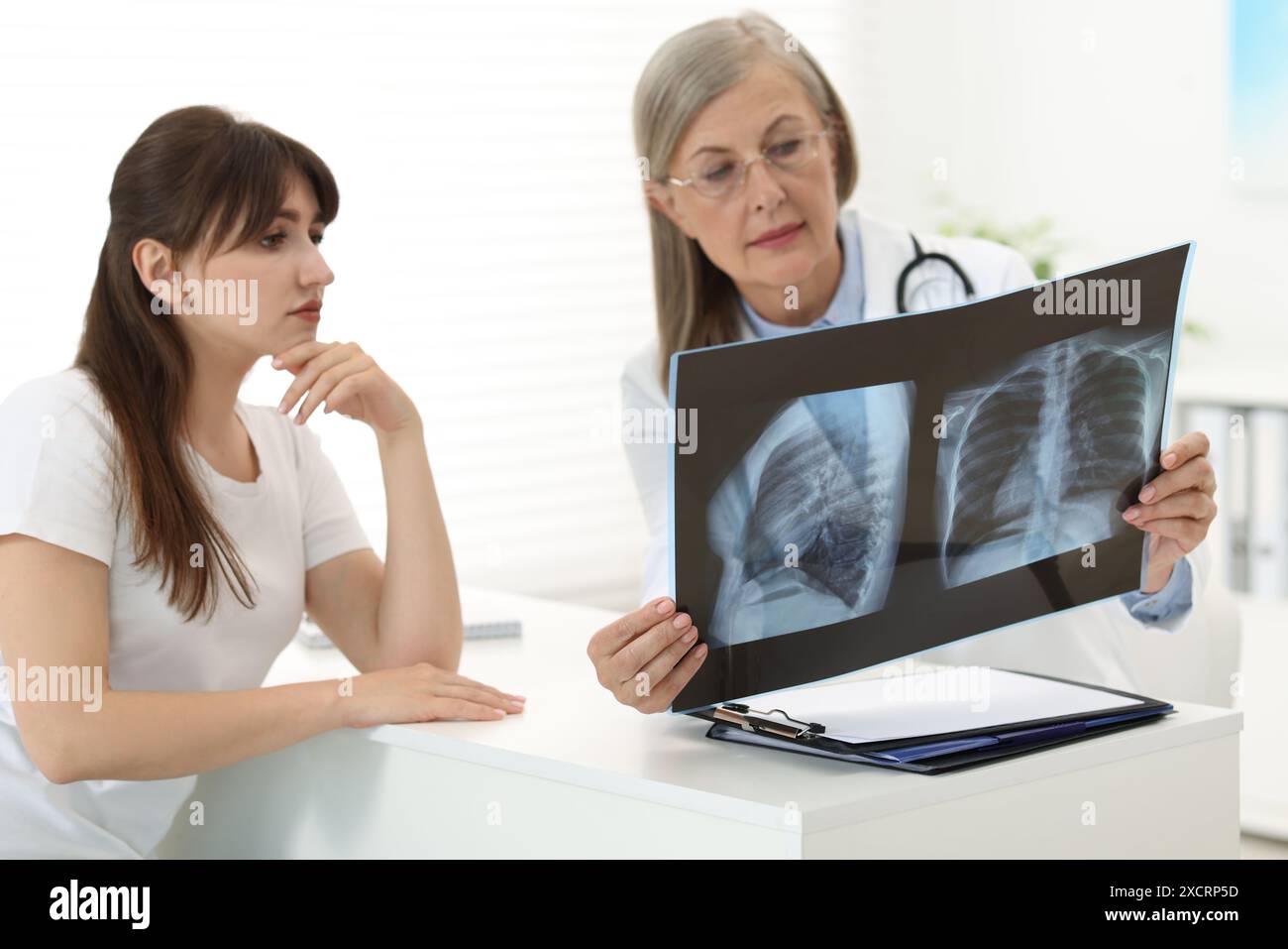 Lung disease. Doctor showing chest x-ray to her patient in clinic Stock ...