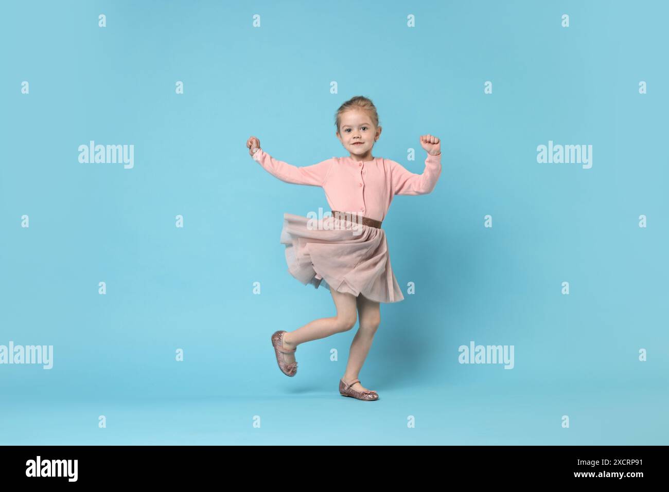 Cute little girl dancing on light blue background Stock Photo - Alamy