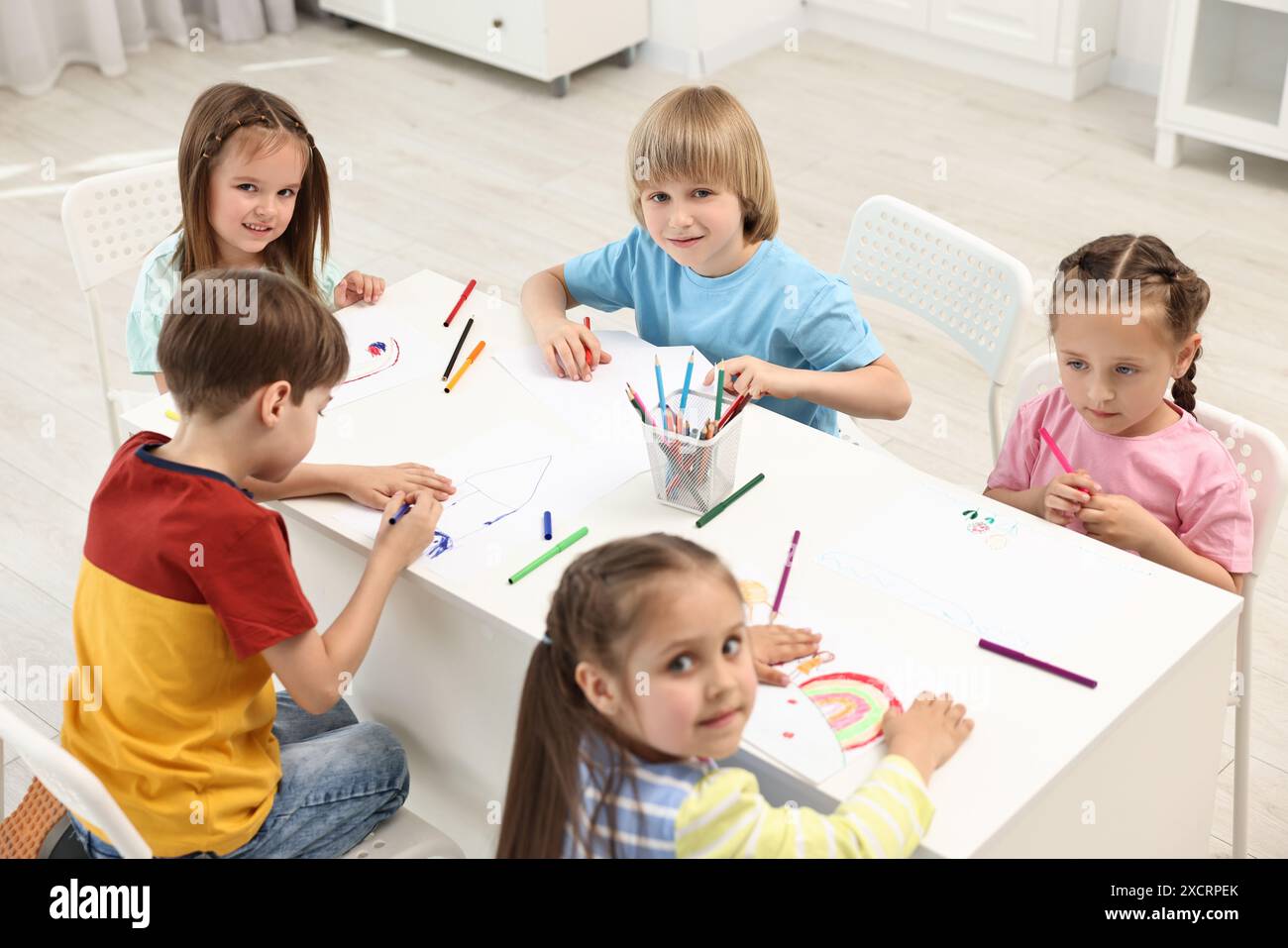 Group of children drawing at table indoors Stock Photo - Alamy