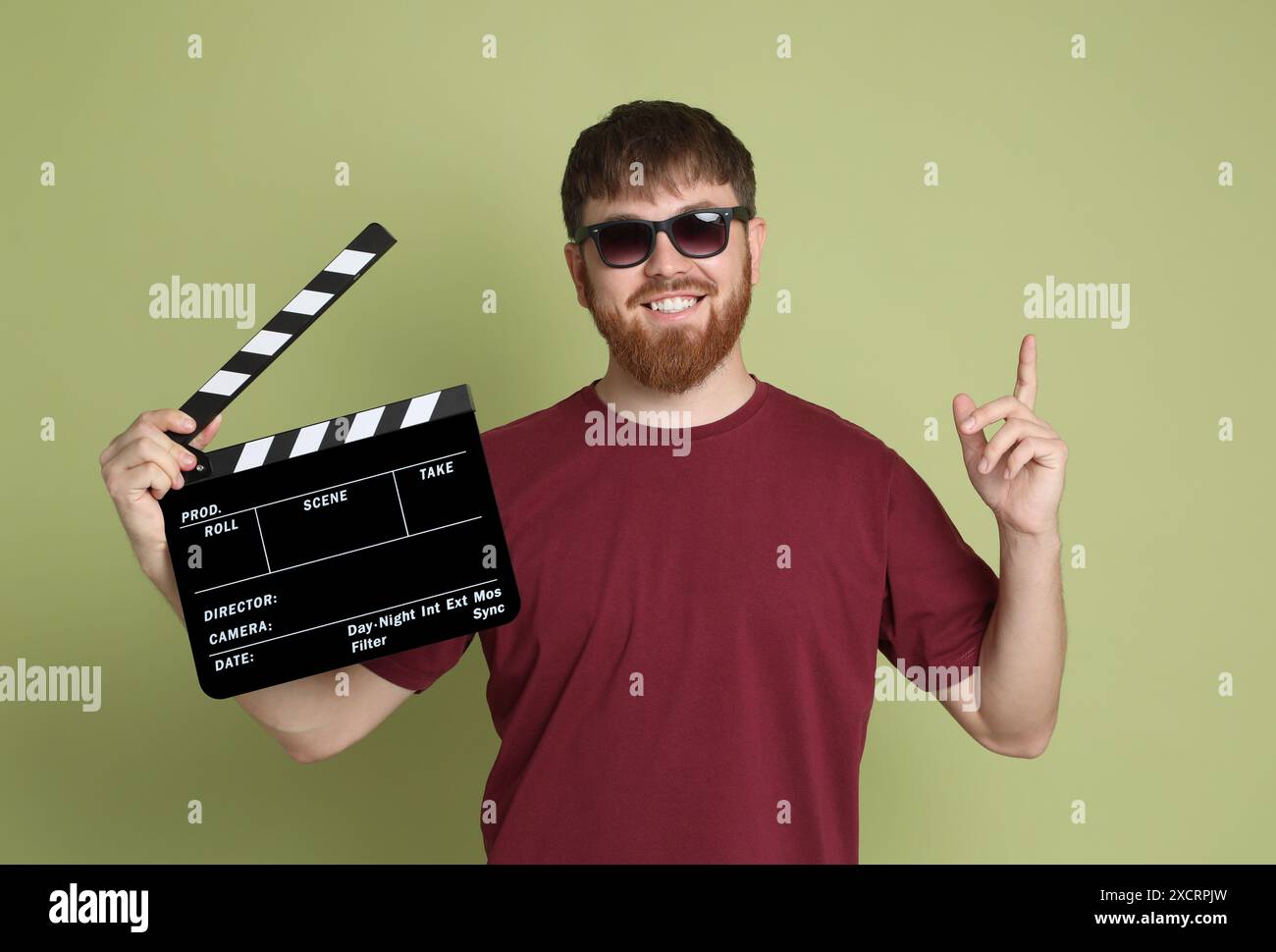 Making movie. Smiling man in sunglasses with clapperboard pointing at ...