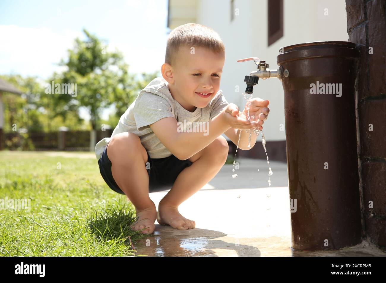 Water scarcity. Cute little boy drinking water from tap outdoors, space ...