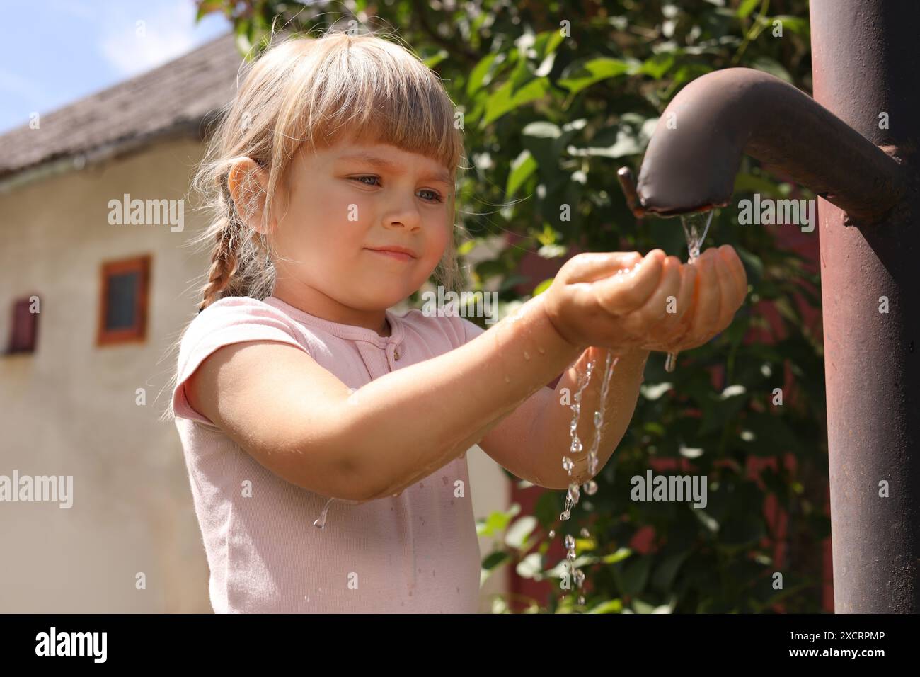 Water scarcity. Cute little girl drawing water with hands from tap ...