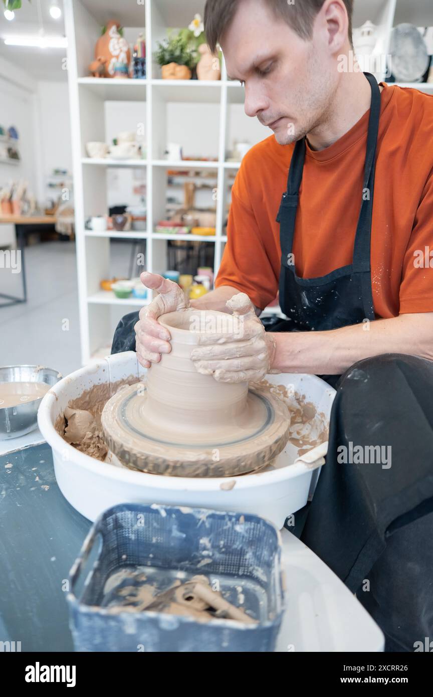 A potter works on a potter's wheel to smooth the surface of a vase ...