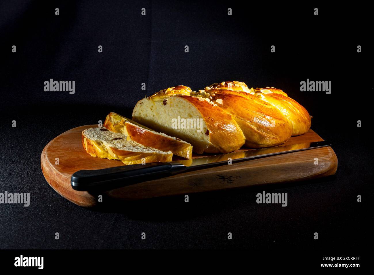 A freshly baked braided bread loaf, topped with almonds and filled with ...