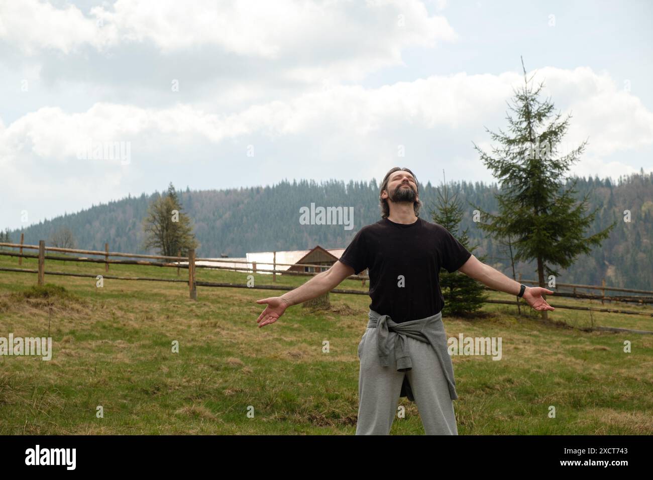 happy caucasian man in a clearing against the backdrop of mountains. He ...