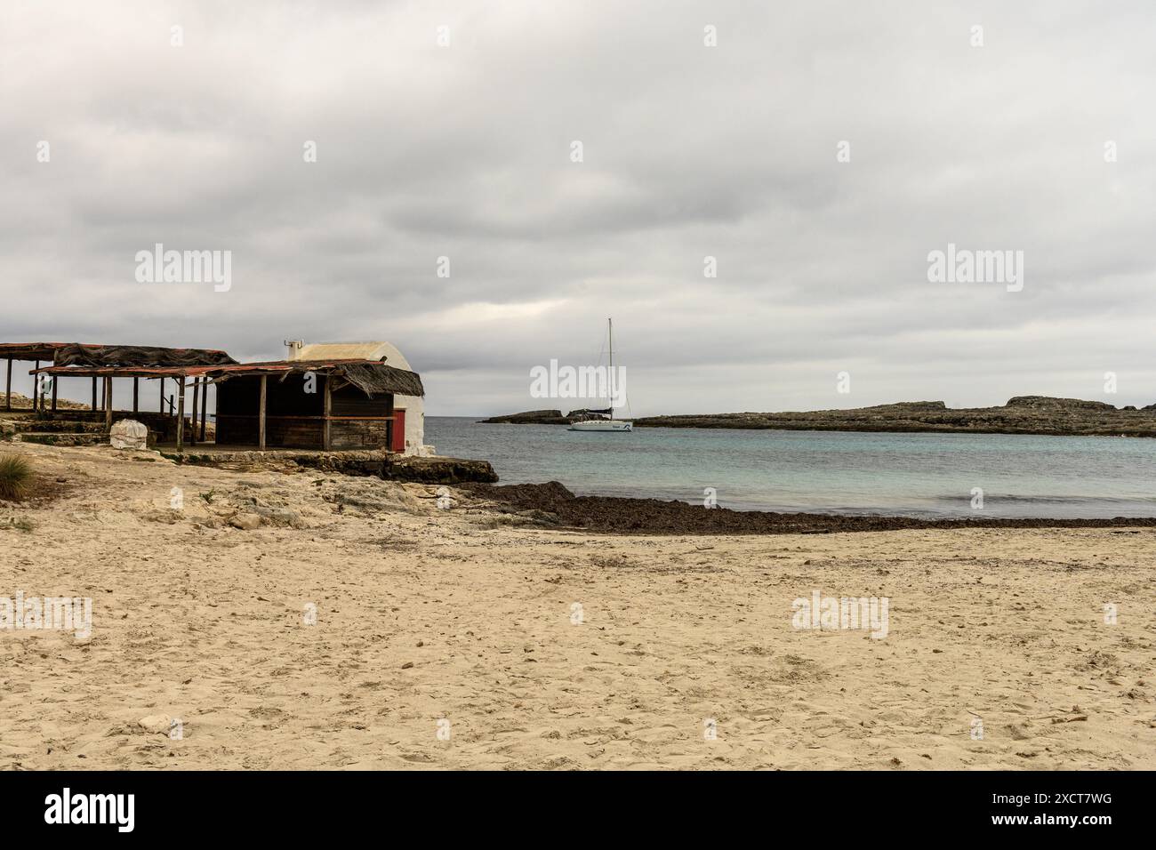 A rustic beach hut stands by the rocky shoreline of Cala Binibeca ...