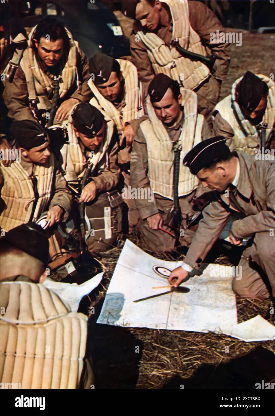A photograph shows an operations briefing between members of the German ...
