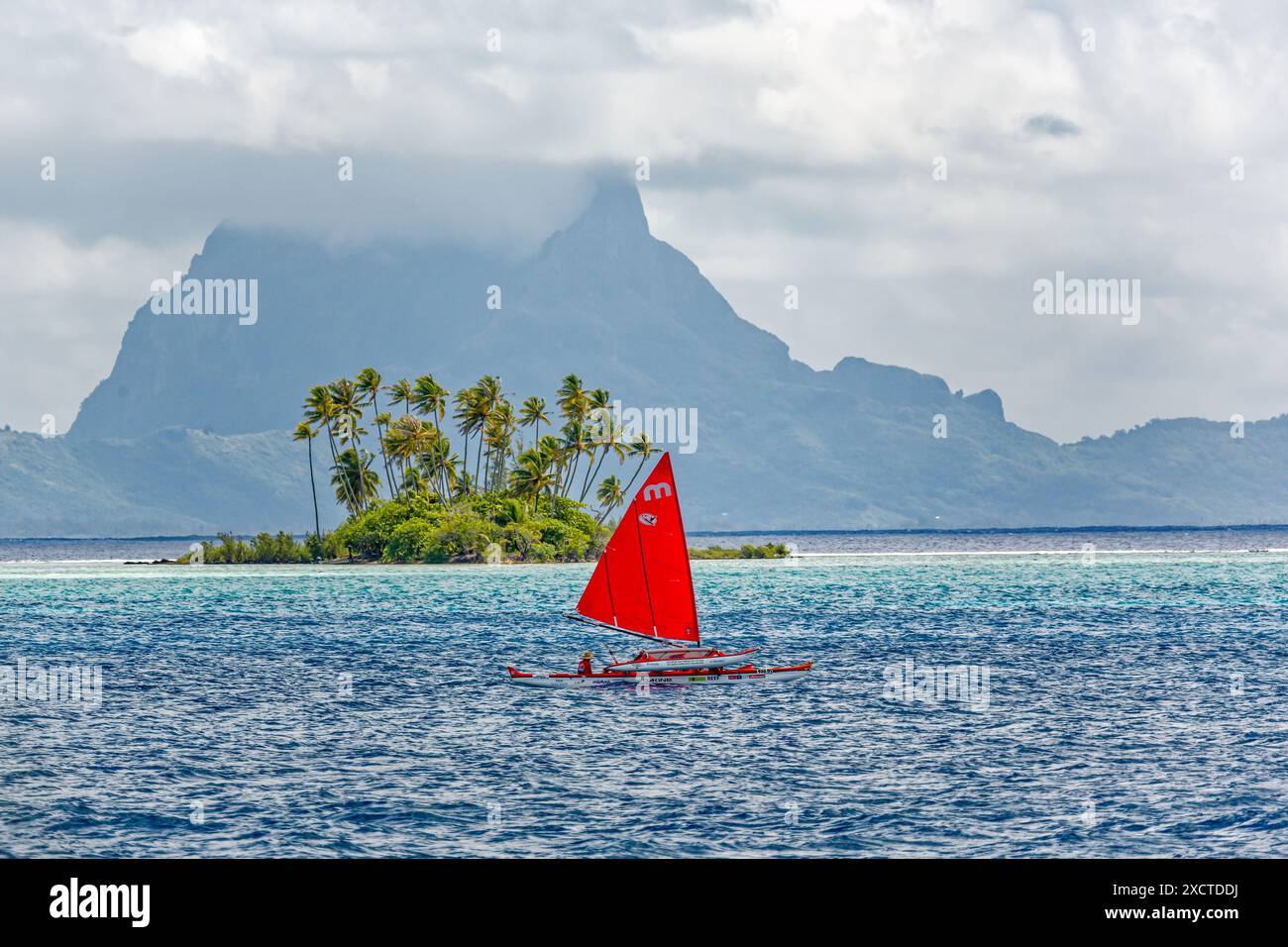 FRENCH POLYNESIA. TAHAA ISLAND. A TRADITIONAL PIROGUE PASSES A MOTU ON ...