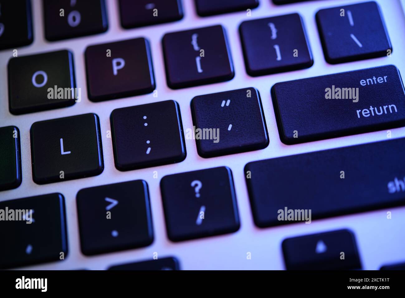 A detailed view of a modern keyboard highlighting the enter and return keys under a blue ...