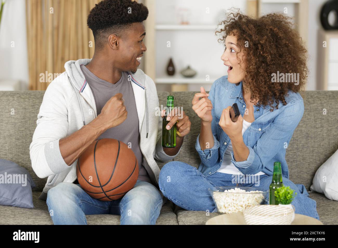 young couple watching basketball game on the sofa Stock Photo - Alamy