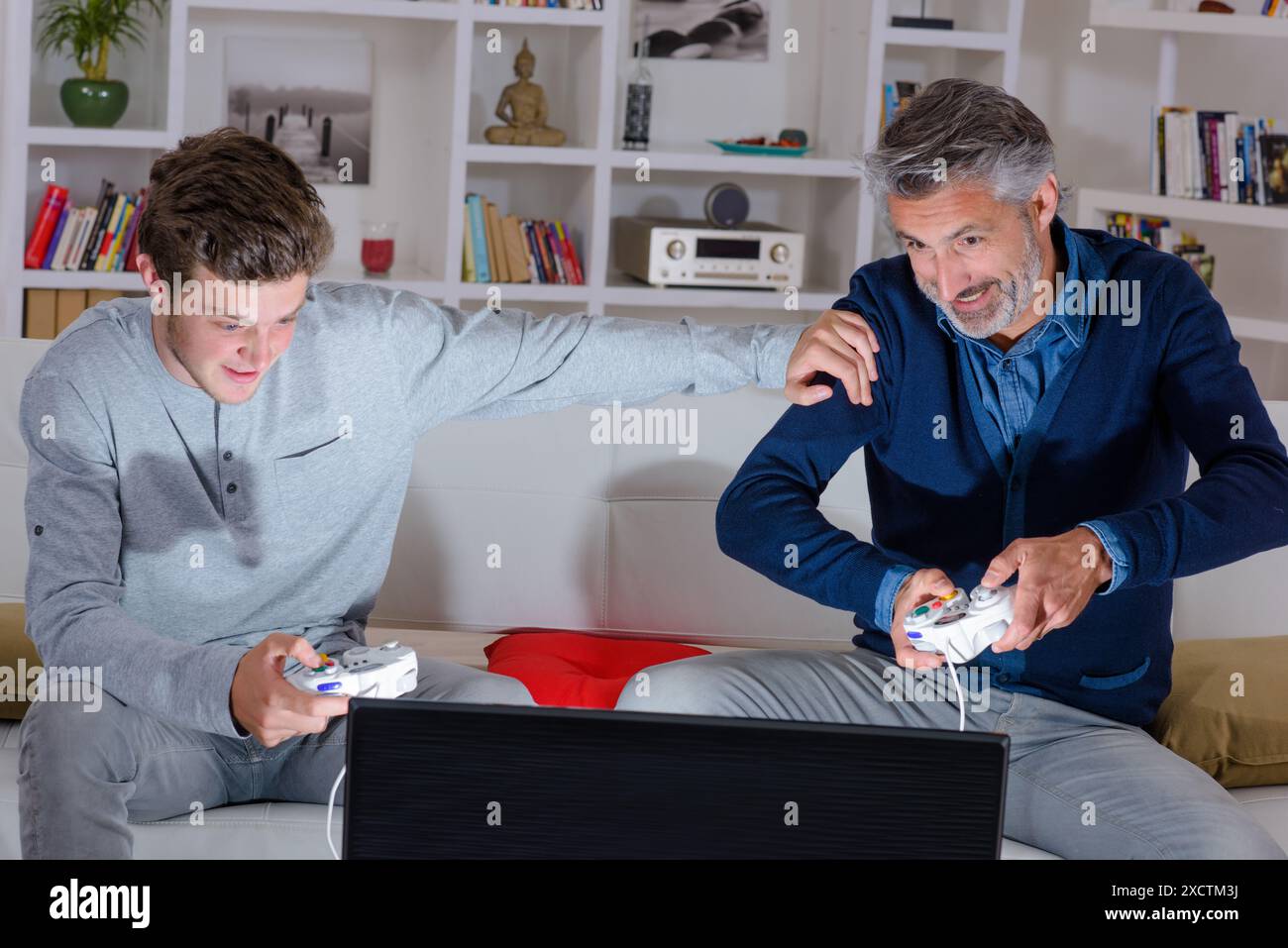 Adult and young man competing at computer game Stock Photo - Alamy