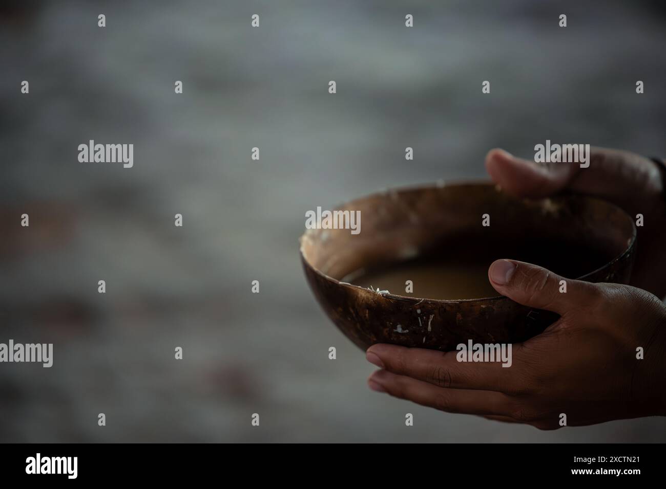 close-up of indigenous hands cradling a bowl of Chicha, a beverage made ...