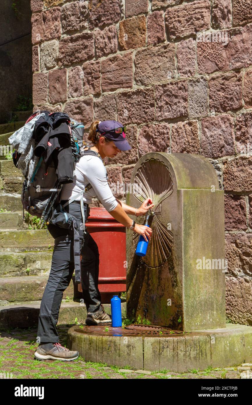 Pilgrim filing a water bottle from a fountain in the French town of ...