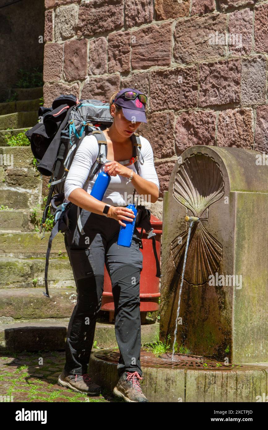Pilgrim filing a water bottle from a fountain in the French town of ...