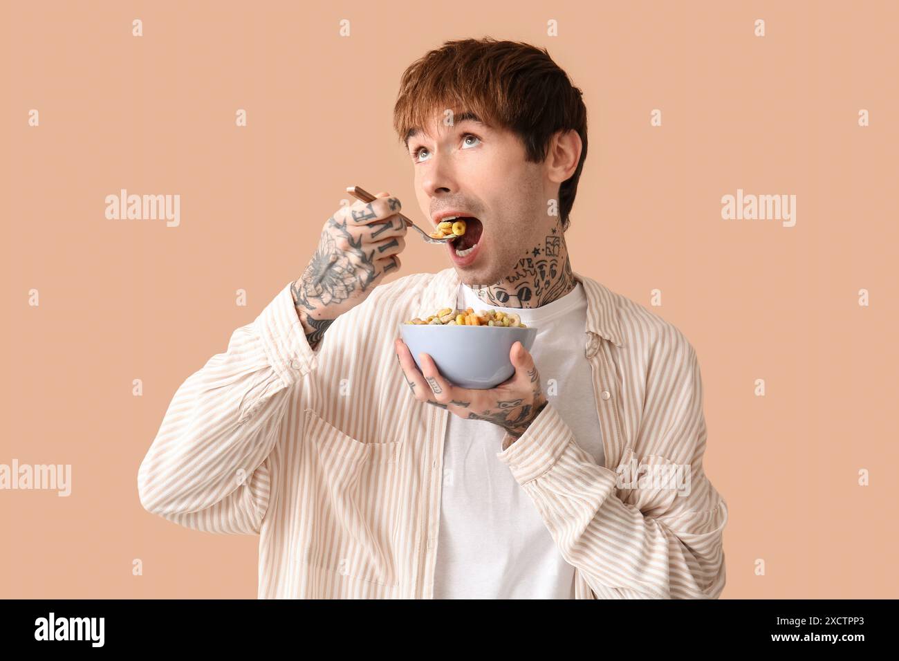 Man eating cereal rings on beige background Stock Photo - Alamy