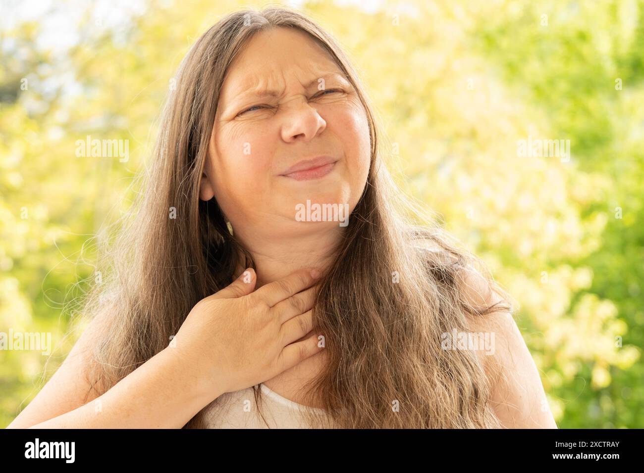 close-up mature female neck, patient holding affected area ...