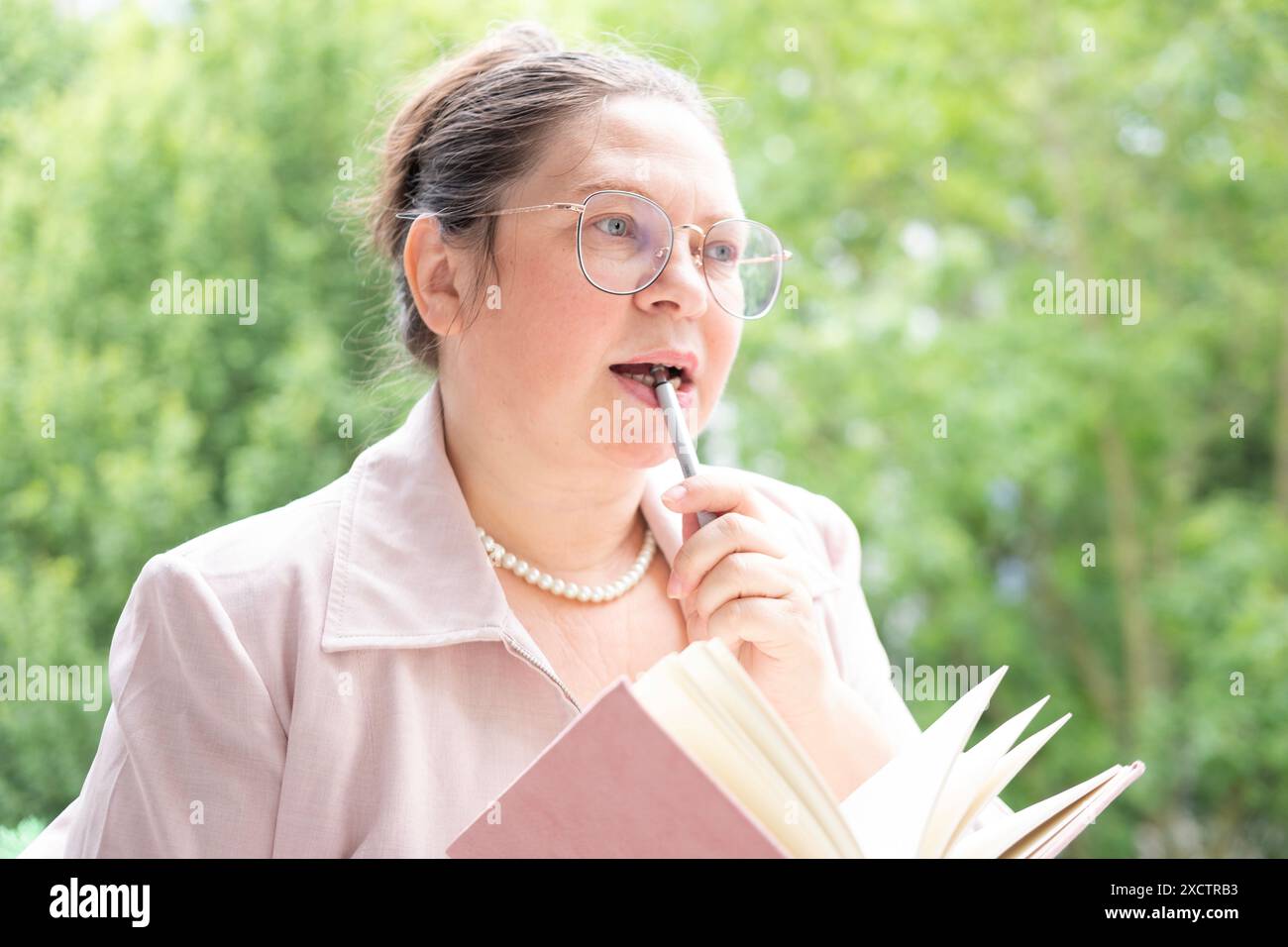 elegant Mature businesswoman, woman in pink jacket keeps records ...