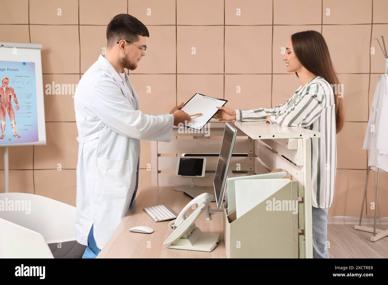Male receptionist giving patient filling form at hospital Stock Photo ...