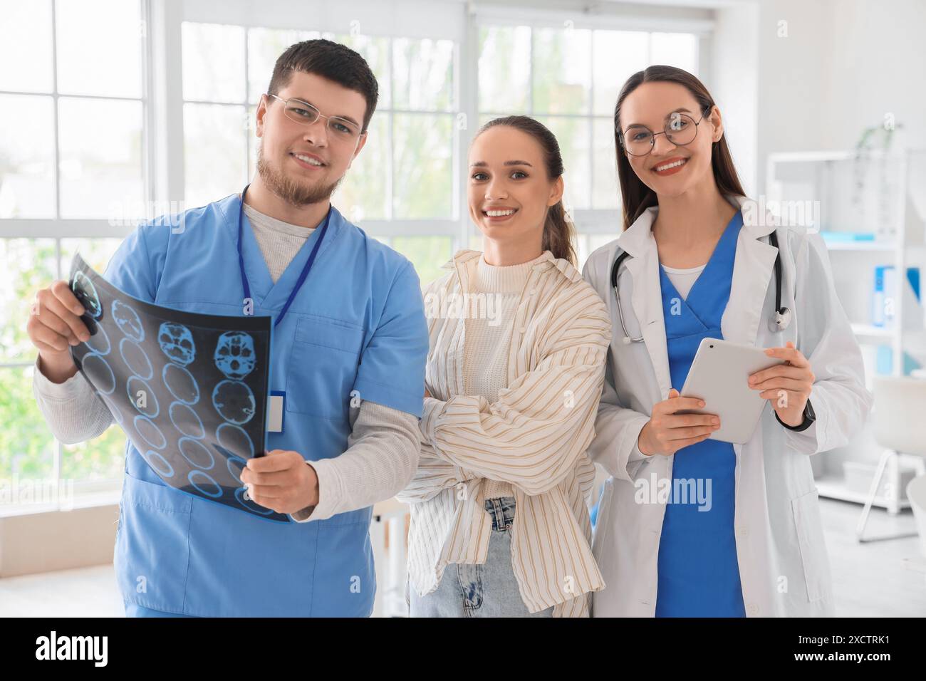 Smiling doctors with MRI scan and patient in clinic Stock Photo - Alamy