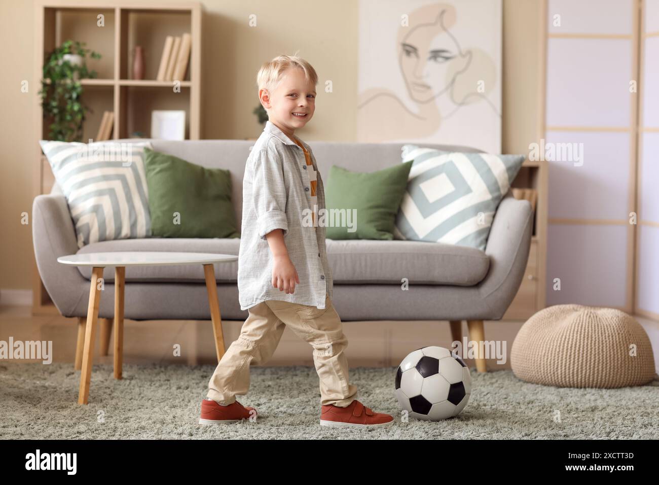 Cute little football player with soccer ball at home Stock Photo - Alamy