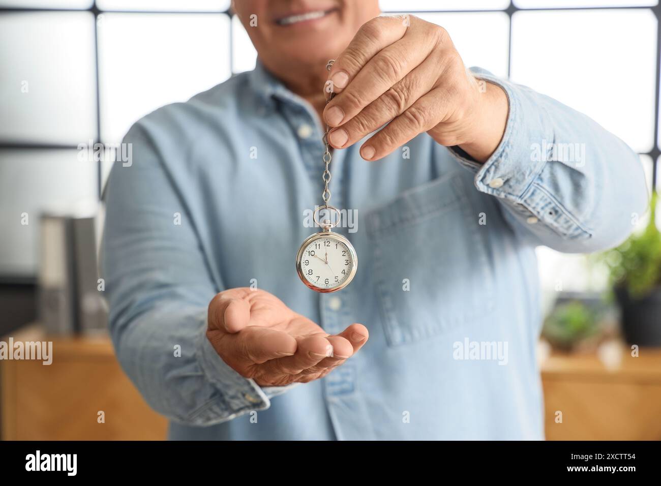 Male hypnotist with pocket watch in office Stock Photo - Alamy