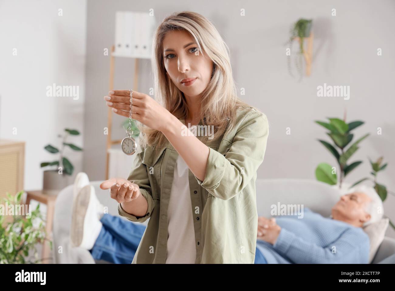 Female hypnotist with pocket watch in office Stock Photo - Alamy