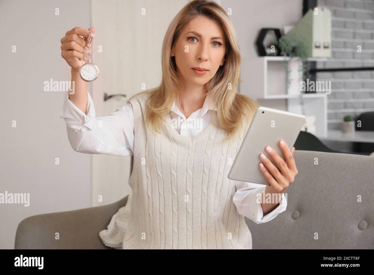 Female hypnotist with pocket watch and tablet computer in office Stock ...
