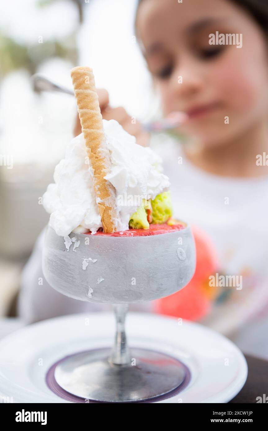 Close-up of a child enjoying a colorful ice cream sundae topped with ...