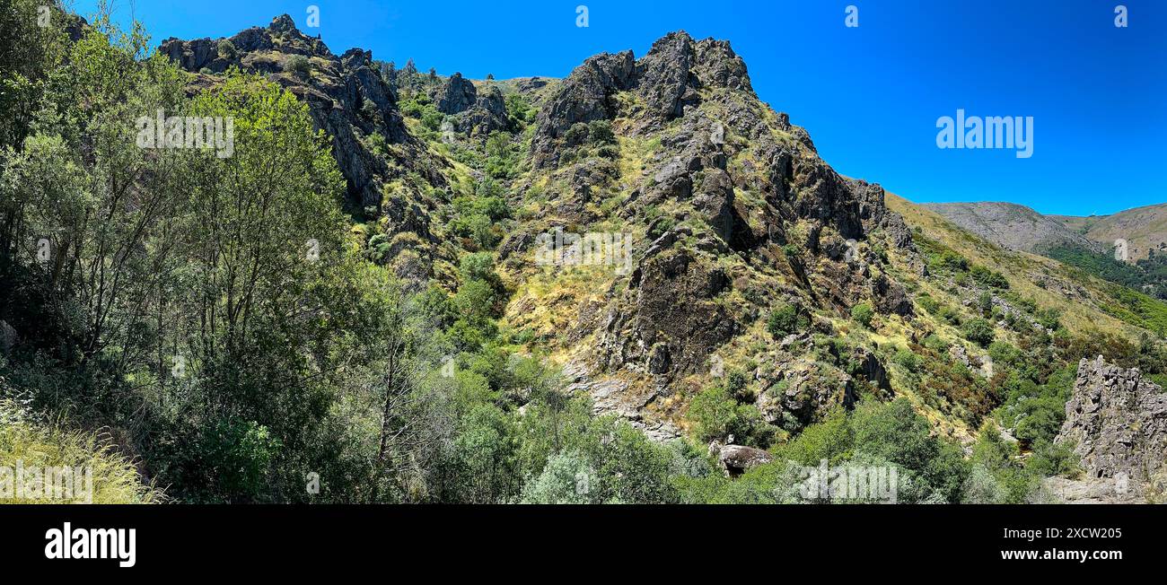 Majestic mountain peaks tower under a clear sky, flanked by verdant ...