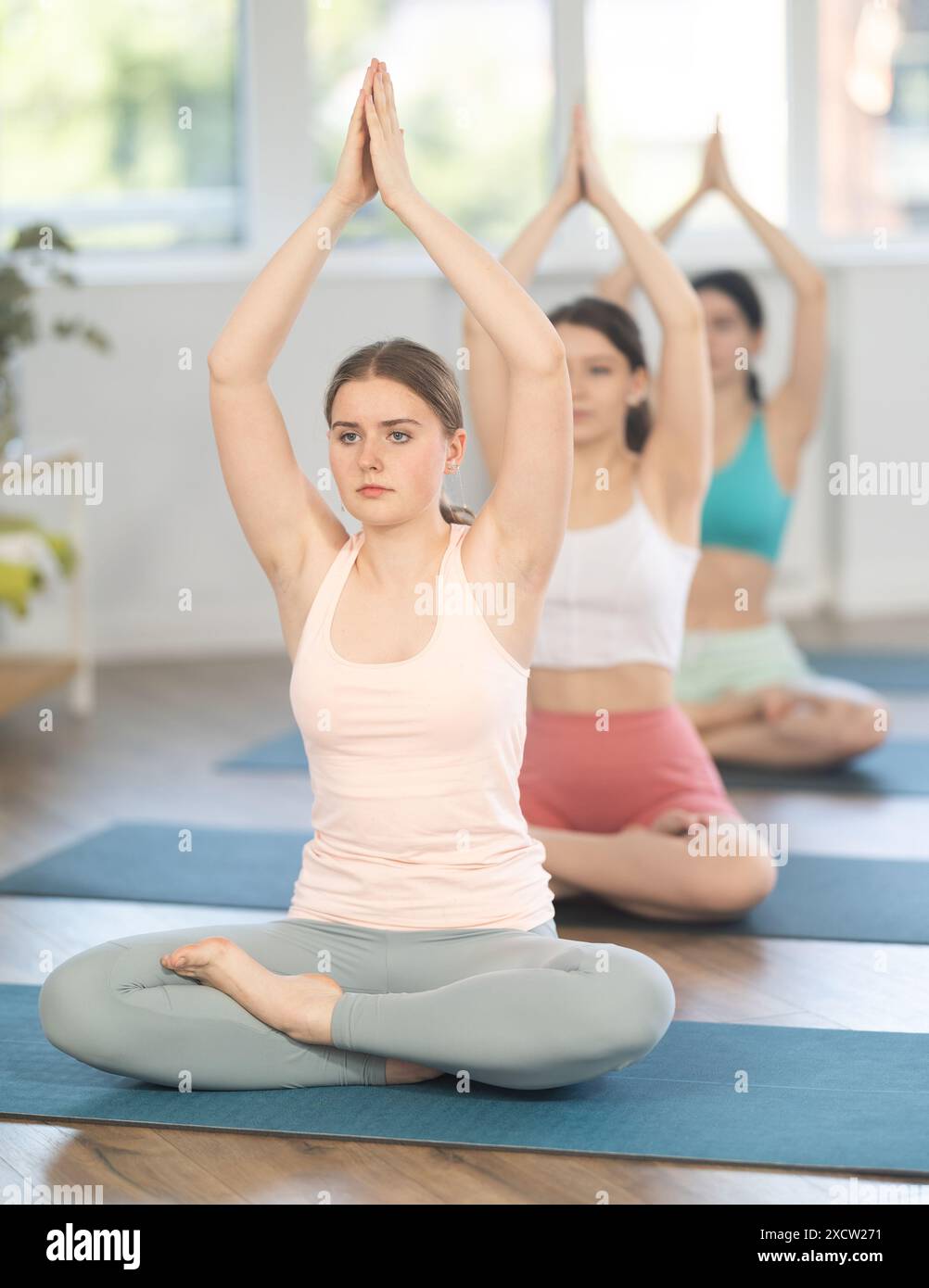 Young girl teaches yoga lesson, shows students technique of performing ...