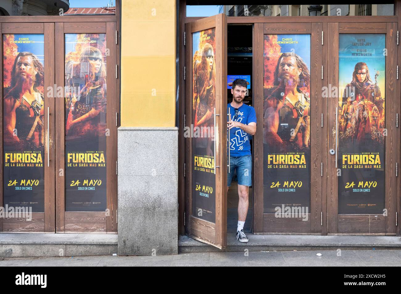 Moviegoers leave a cinema adorned with advertisement posters for the ...