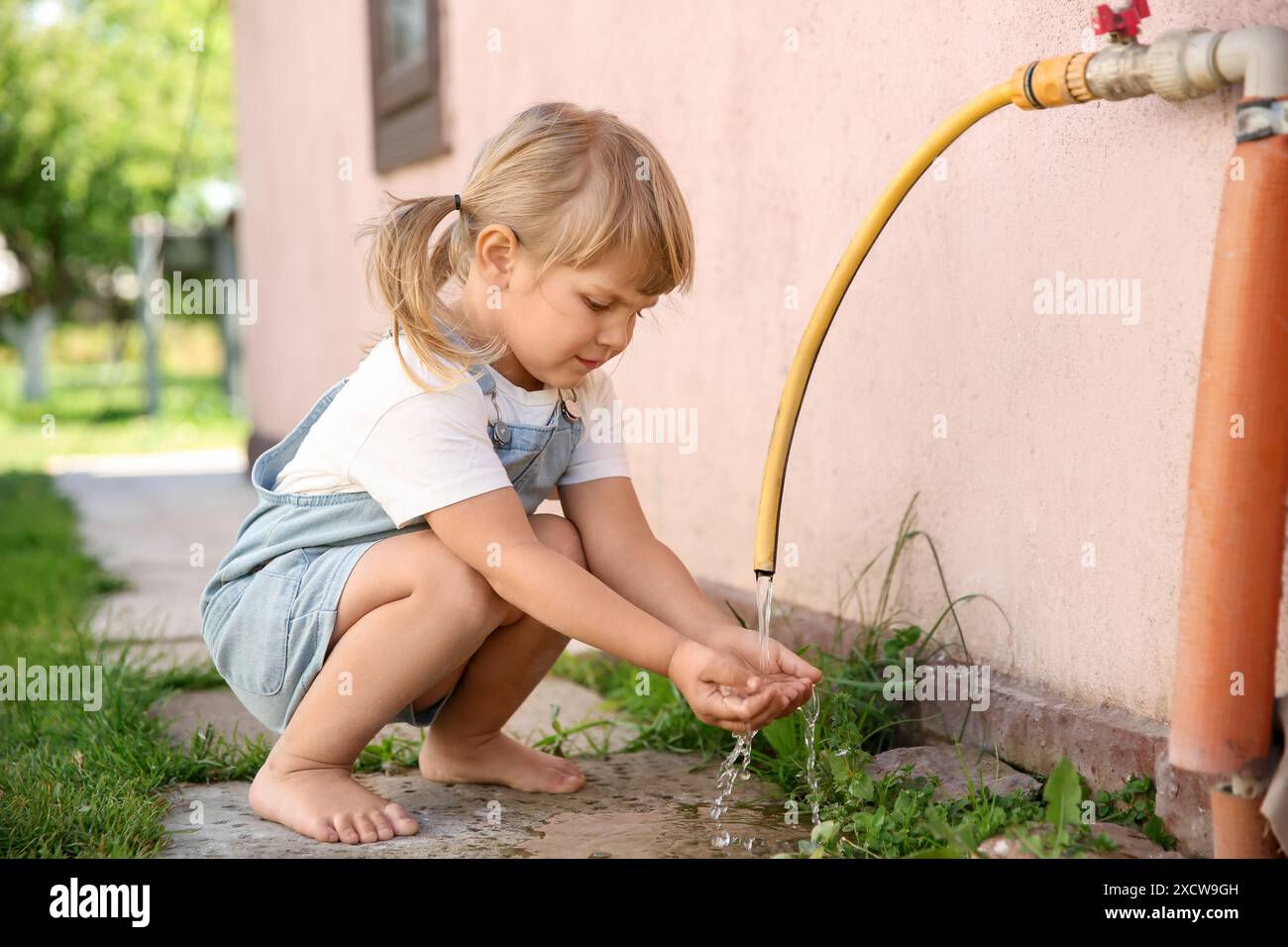 Water scarcity. Cute little girl drawing water with hands from tap ...
