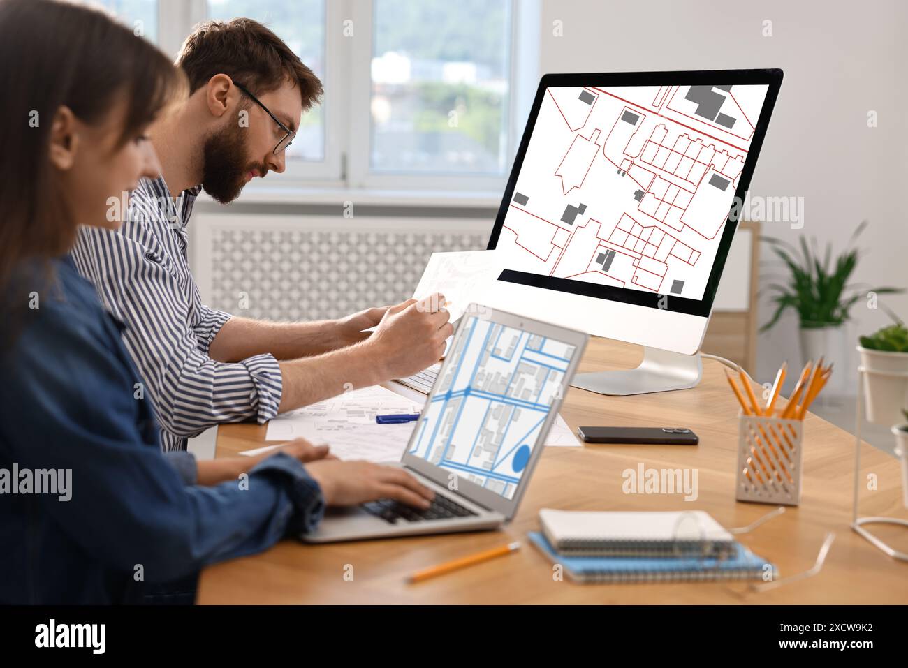 Cartographers working with cadastral maps at table in office Stock ...