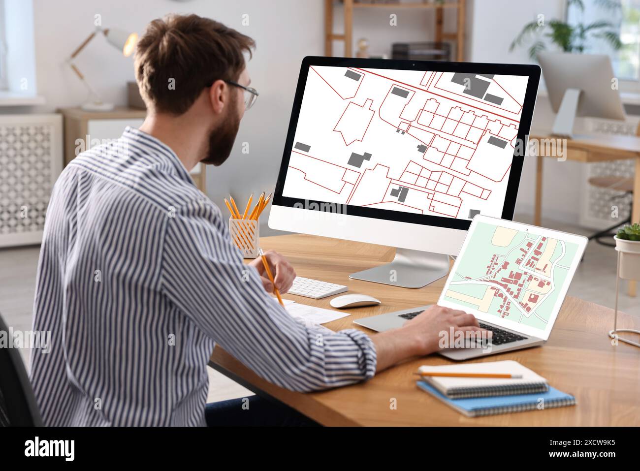 Man working with cadastral map on computers at table in office Stock ...