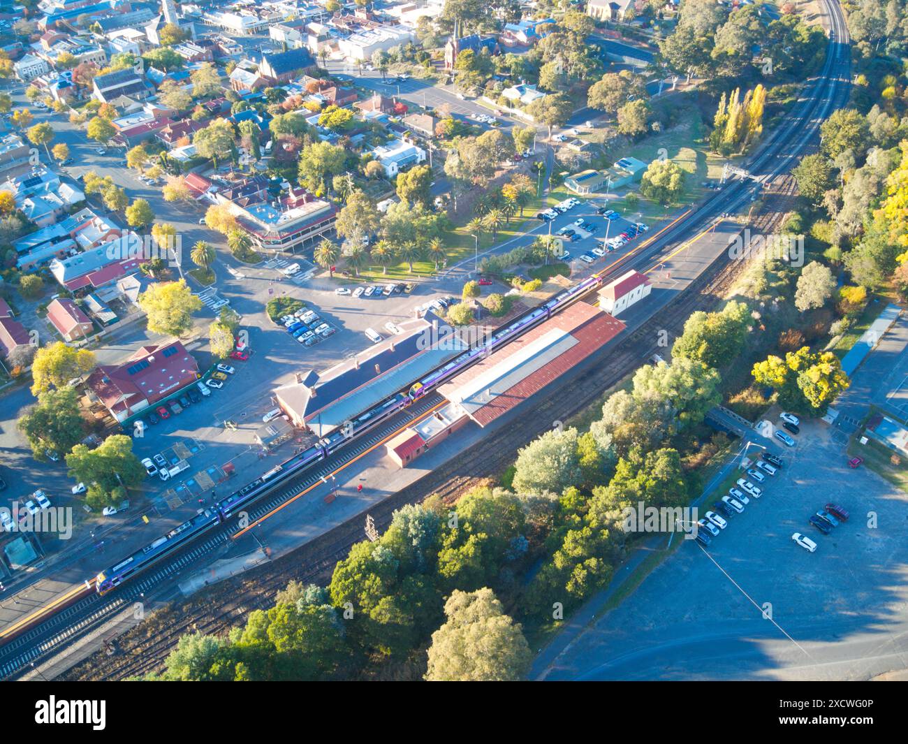 Railway tracks aerial view with train in station showing car parks ...