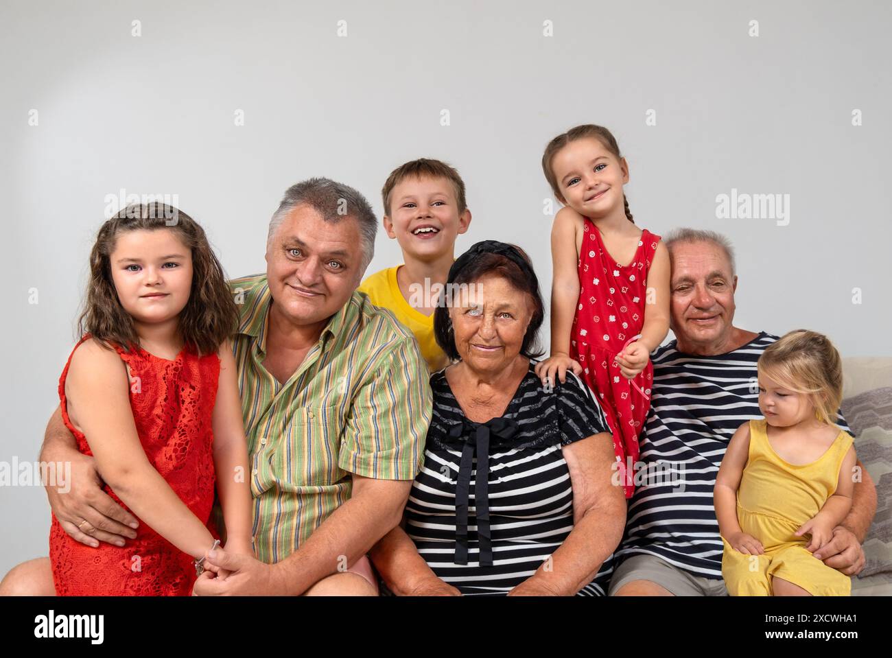 Family portrait of great grandparents with children on the sofa ...