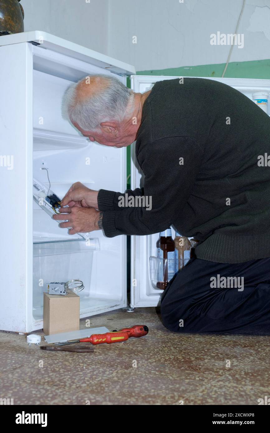 older mature man replacing thermostat on broken down fridge Stock Photo ...