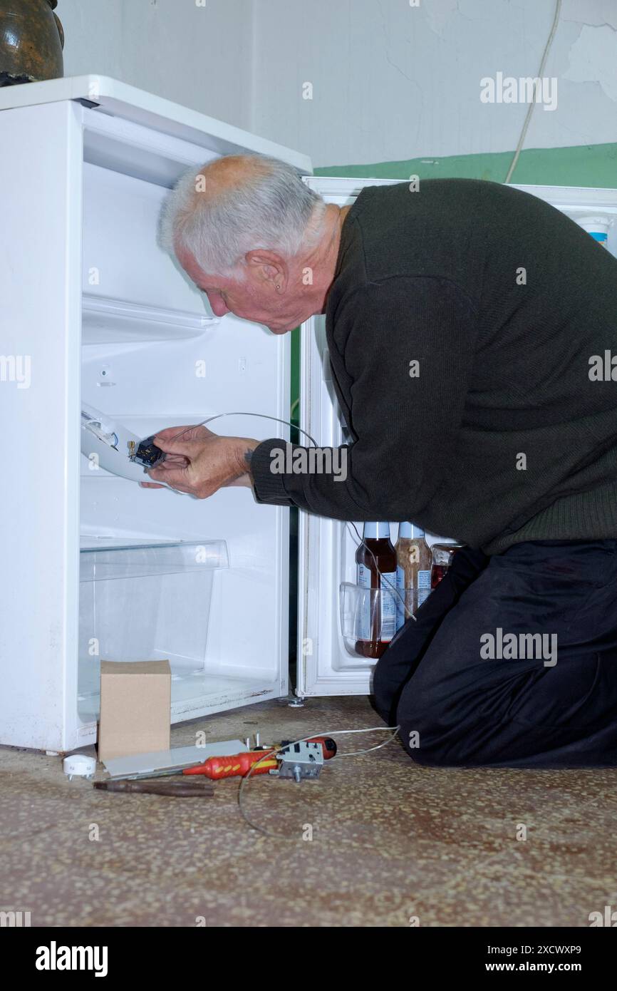 older mature man replacing thermostat on broken down fridge Stock Photo ...