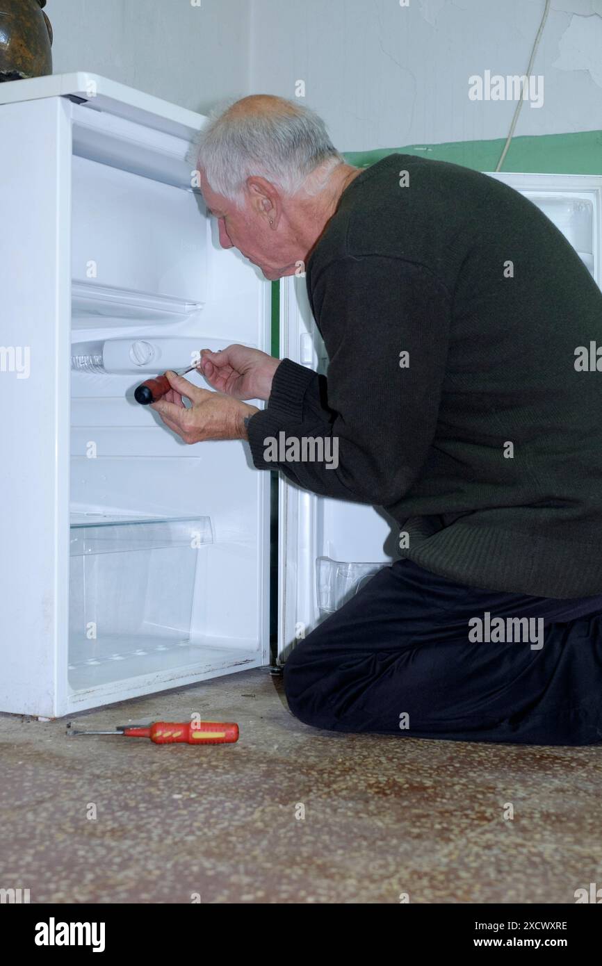 older mature man replacing thermostat on broken down fridge Stock Photo ...