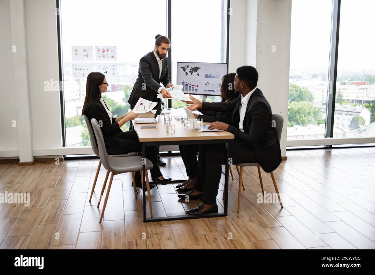 Businessman handing out papers during office meeting Stock Photo - Alamy