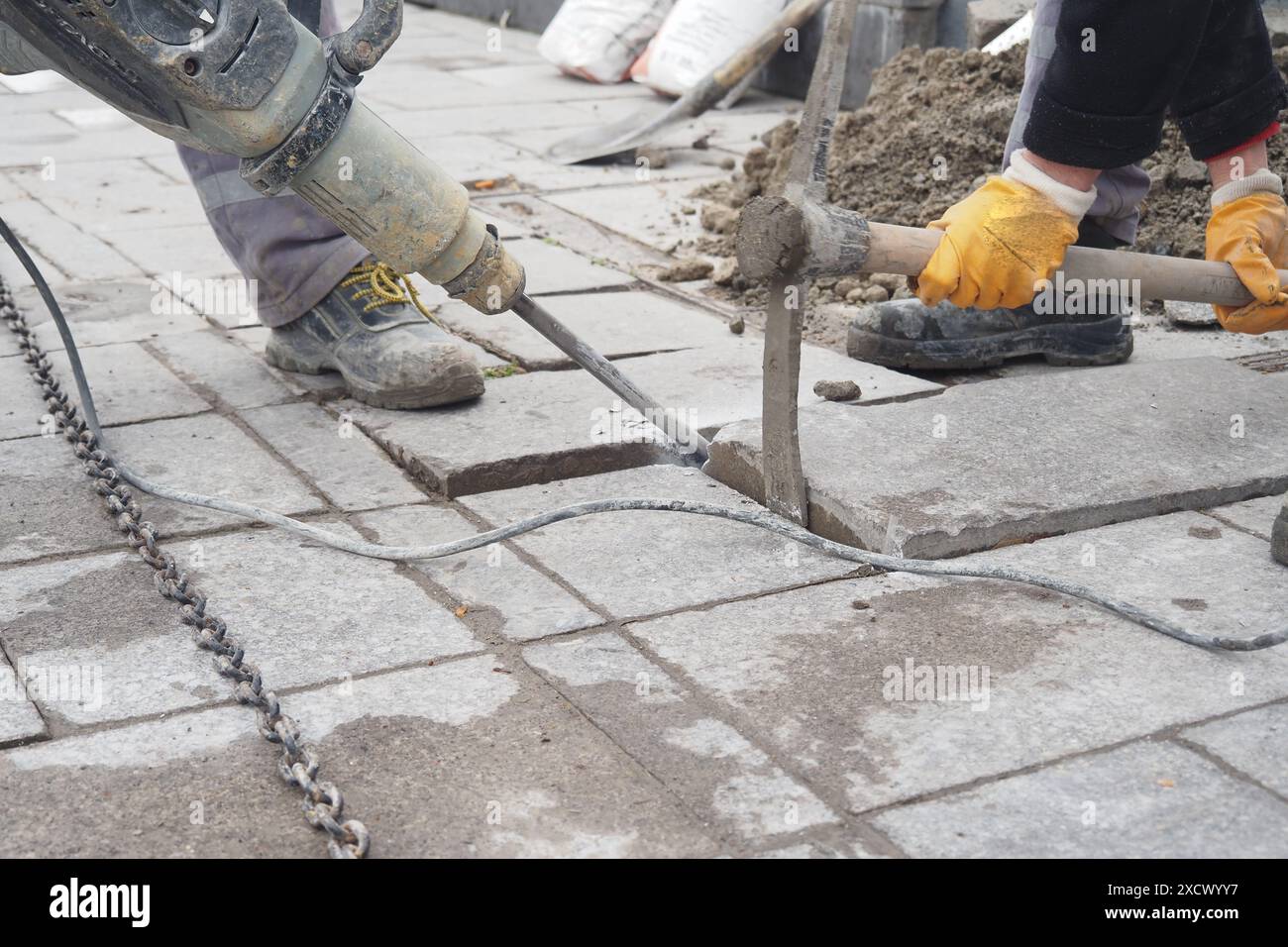 A group of workers using a jackhammer to break and remove concrete ...