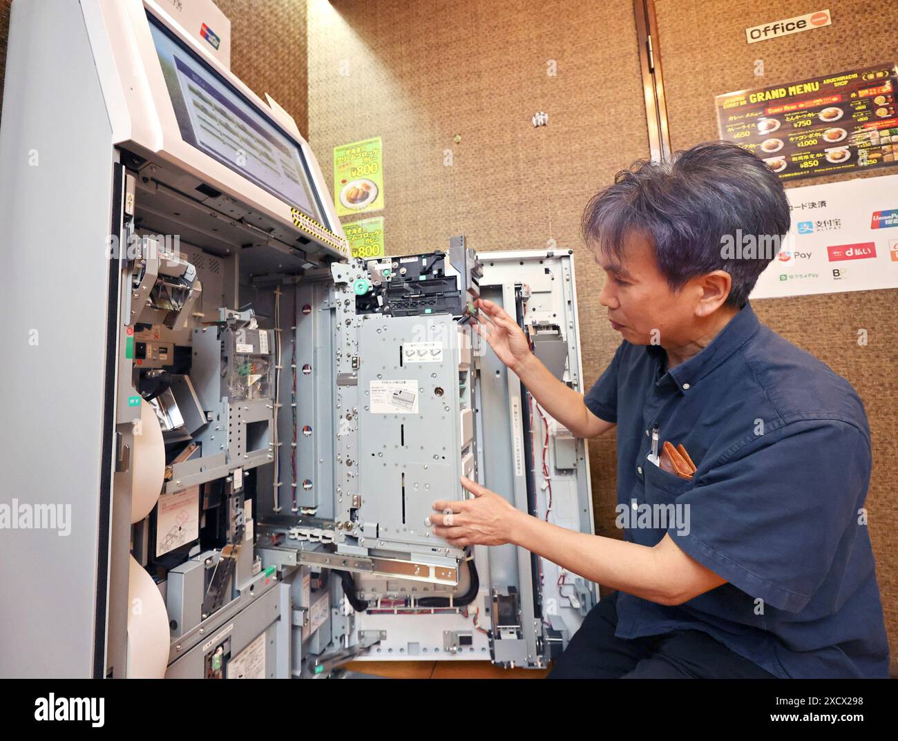 A restaurant owner checks a touch-screen ticket vending machine that is ...