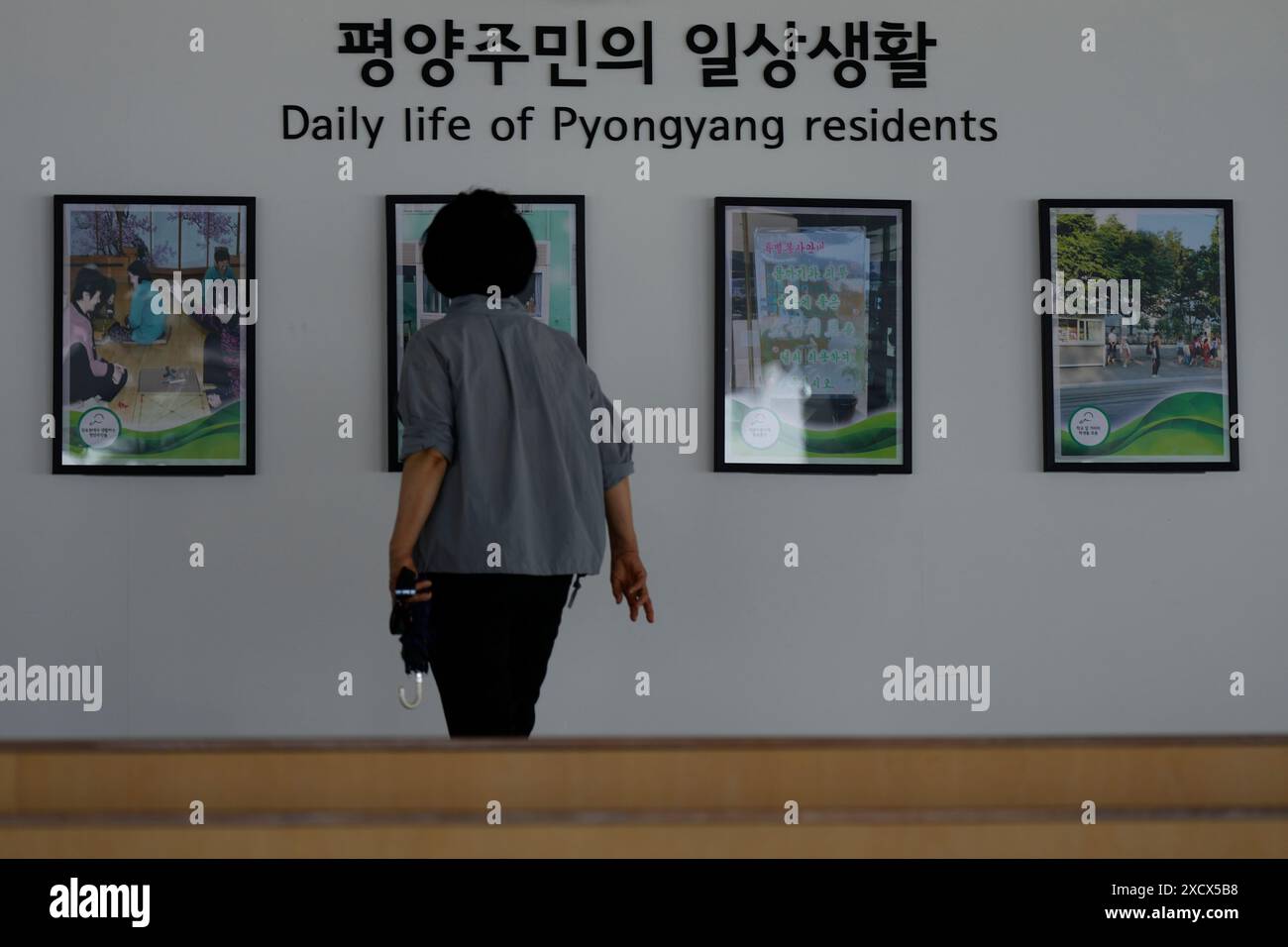 A visitor walks in front of pictures showing the North Korea's capitol ...