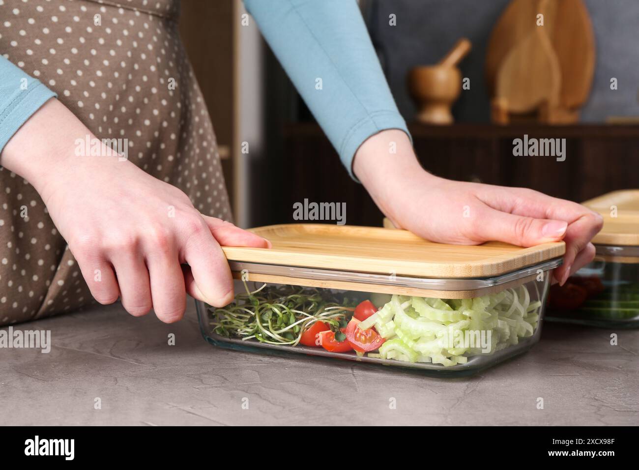 Healthy food. Woman closing glass container with fresh vegetables at ...