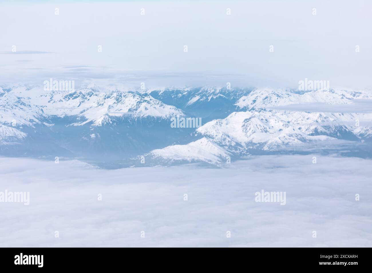 Aerial view of fluffy white clouds and snowy peaks. Snow covered ...