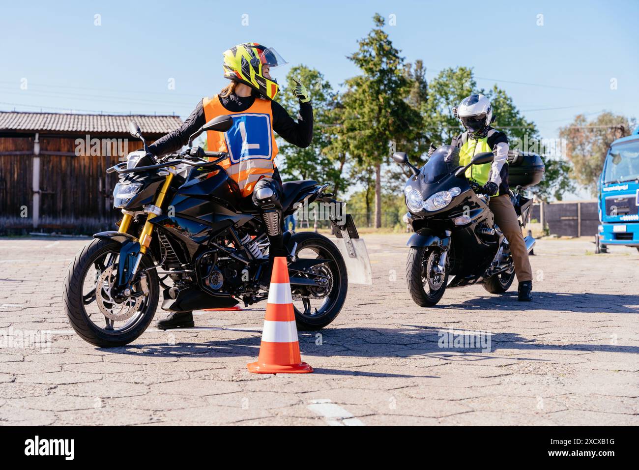 Motorcycle driving school concept. Charming woman in orange vest with ...