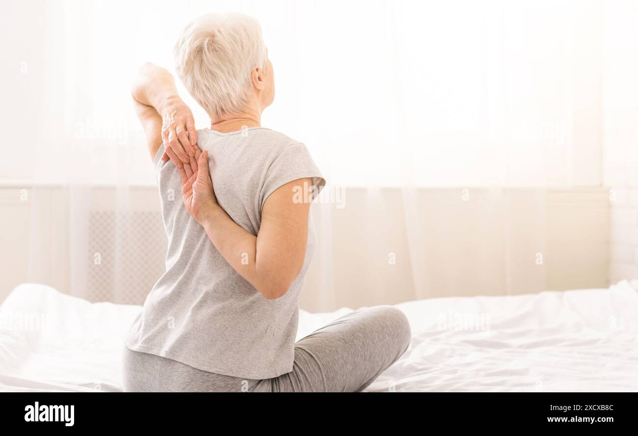 Elderly woman touching her hands behind her back Stock Photo - Alamy